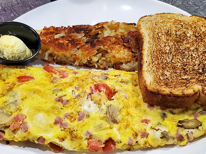 This isn't just an omelet—it's a masterpiece of ham, cheese, and vegetables tucked inside fluffy eggs, with perfectly golden toast standing guard.