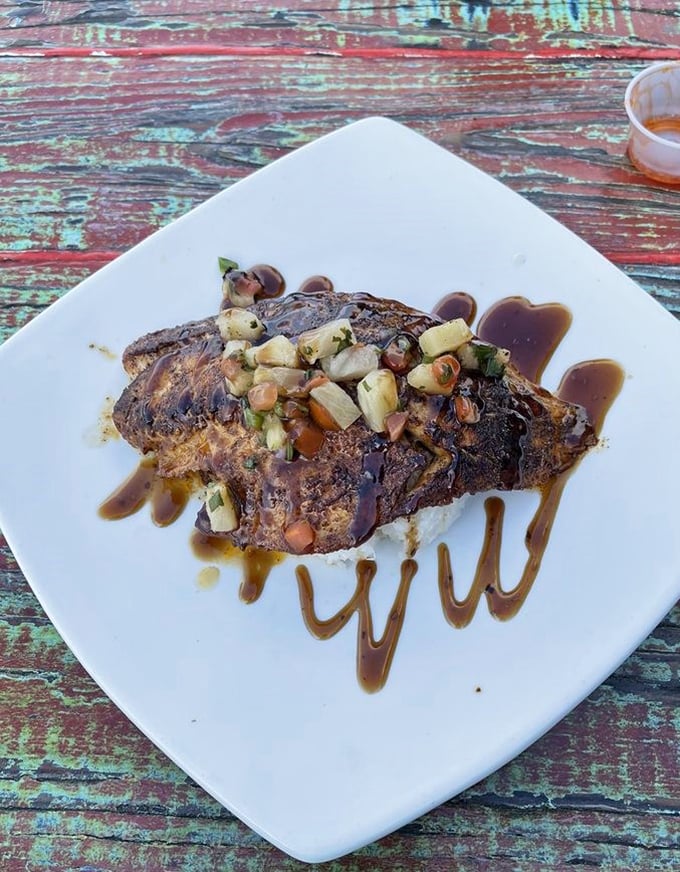 This blackened fish with pineapple salsa isn't just dinner—it's edible artwork. The sauce swirls are like the chef's signature on a masterpiece.