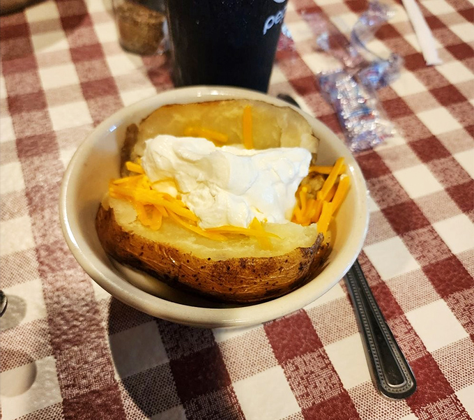 Not just a baked potato—it's a canvas of comfort topped with a snow-capped mountain of sour cream and a golden avalanche of cheese.