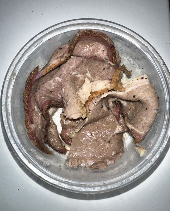 The brisket whispers secrets of patience - 14 hours in the smoker transforms tough muscle into tender, pink-ringed slices of pure satisfaction.