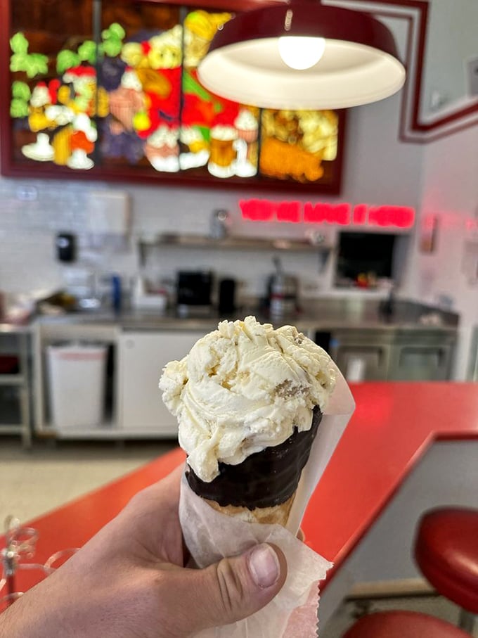 The classic waffle cone and vanilla scoop—sometimes the simplest pleasures are the most profound, especially against that colorful backdrop.