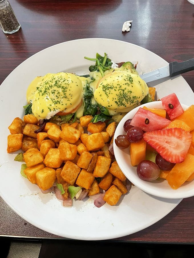 Eggs Benedict that belongs in the breakfast hall of fame—hollandaise so velvety it should be illegal, with a side of fresh fruit for "balance."