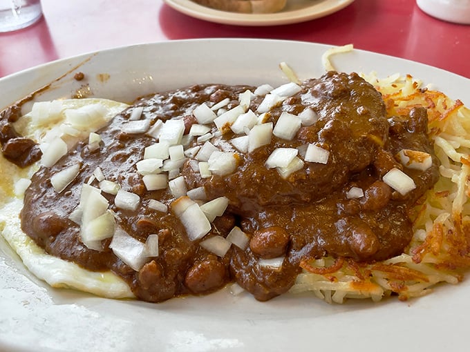 The legendary St. Louis "Slinger" in its natural habitat – where hash browns bravely support a mountain of chili in a delicious architectural marvel.