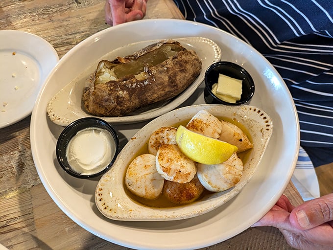 Perfectly seared scallops alongside a fluffy baked potato—proof that sometimes the simplest combinations create the most memorable meals.