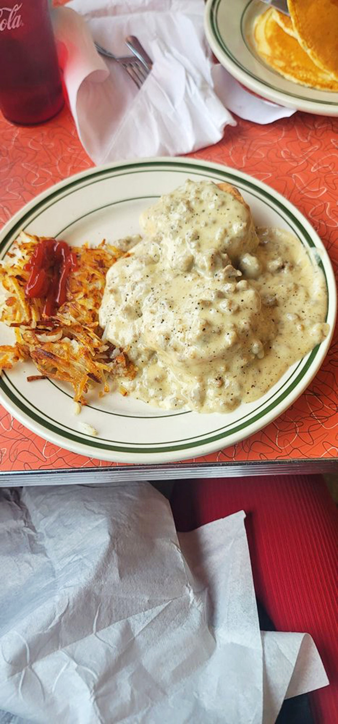 Biscuits and gravy: the breakfast that hugs you from the inside. Creamy, peppery gravy blankets a fluffy biscuit while crispy hash browns stand guard.