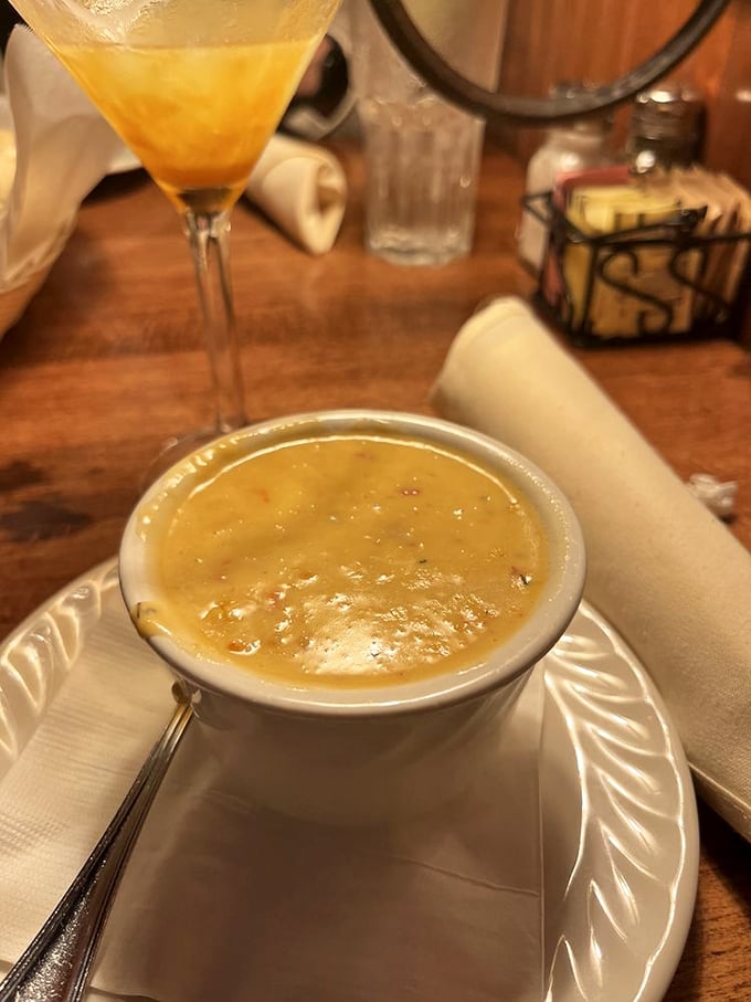 A bowl of liquid gold that proves soup isn't just a starter—it's a soul-warming experience worthy of that fancy martini in the background.