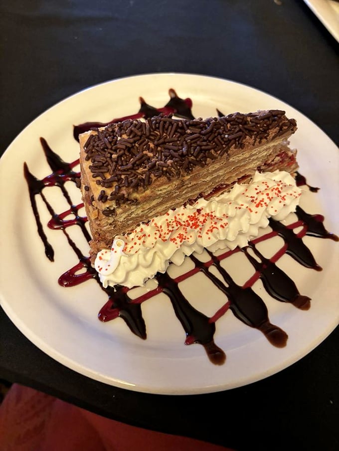 Dessert that demands a moment of silence. Chocolate layered cake with whipped cream and artistic sauce drizzles—calories that are absolutely worth the splurge.