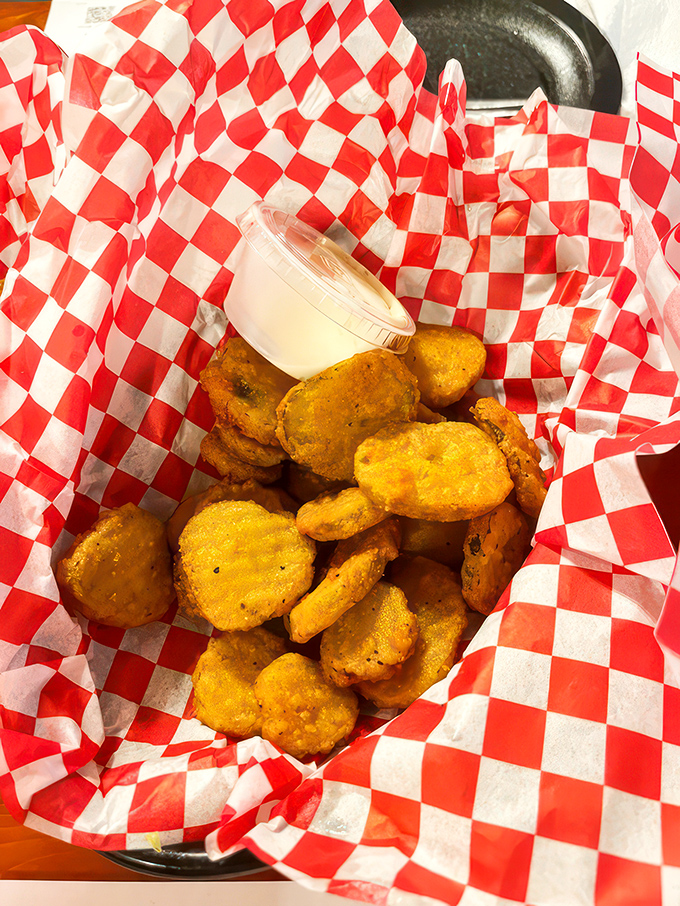 Golden-fried pickle chips nestled in checkered paper – tangy, crunchy little discs of joy that somehow make you hungrier with every bite.