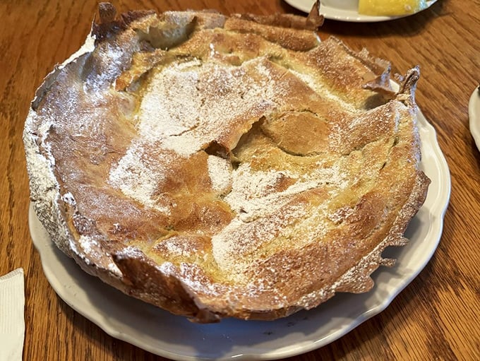 The German pancake rises like a golden souffle, dusted with powdered sugar. It's breakfast architecture that manages to be both impressive and delicious.
