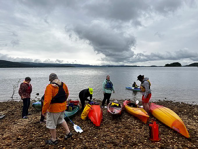 Kayak enthusiasts preparing for aquatic exploration. Even under moody skies, these colorful vessels promise adventures that no Netflix series could ever match.
