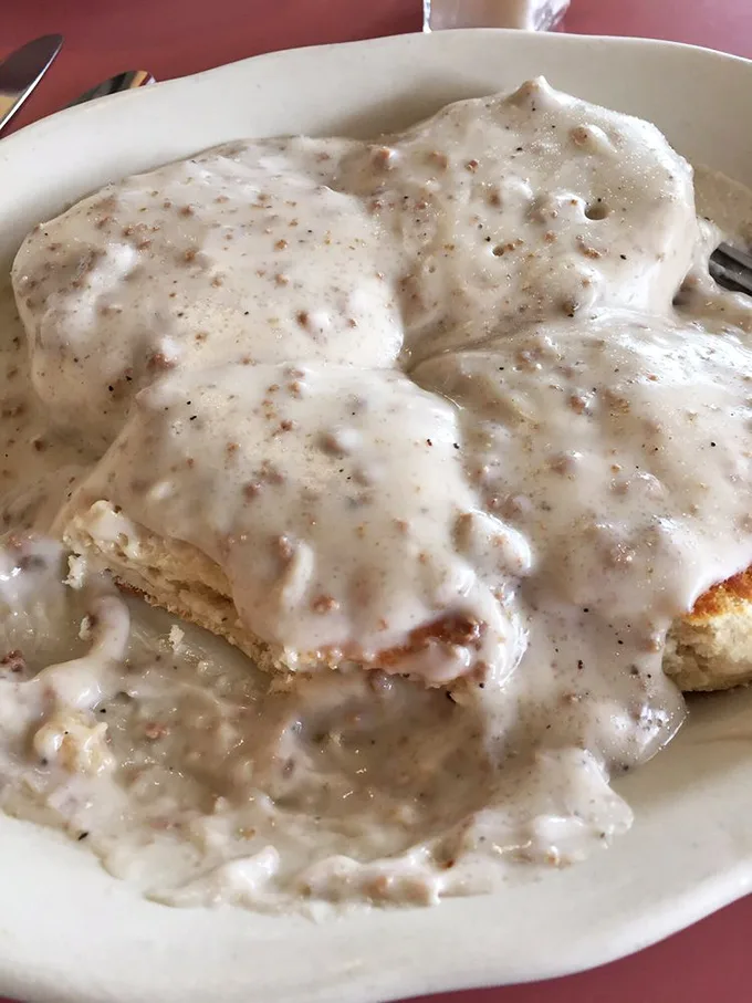 Biscuits lounging beneath a creamy waterfall of gravy—carbs in their most noble form, ready to cure whatever ails you.