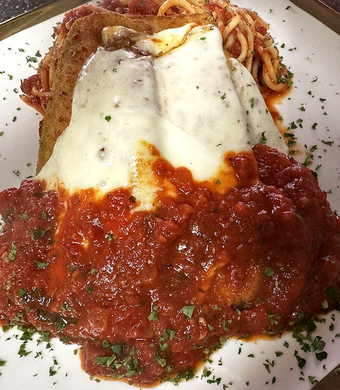 Chicken Parmesan stretching beyond its plate boundaries—a delicious rebellion against portion control that no one's complaining about.