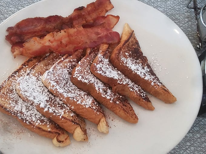 French toast dusted with powdered sugar snow and flanked by bacon guards—breakfast that bridges the sweet-savory divide with delicious diplomacy.