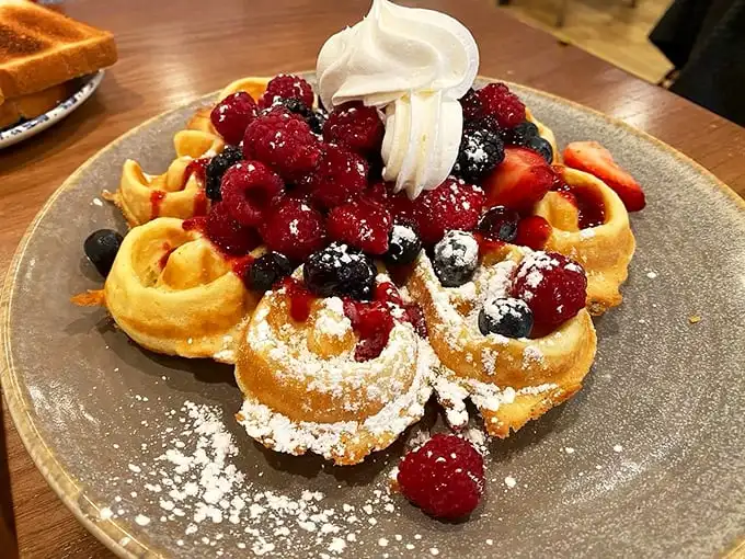 A waffle that's wearing all its jewelry – fresh berries, whipped cream, and powdered sugar create a breakfast that's dressed for success.