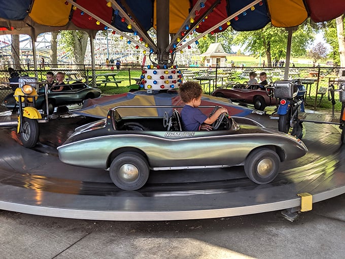 Vintage kiddie cars circle endlessly, piloted by serious-faced youngsters experiencing their first taste of "driving." No license required, just pure childhood joy.