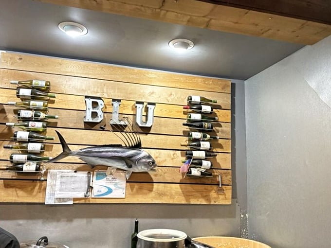 The wall décor proudly announces "BLU" with a mounted fish and wine bottles. Maritime meets merlot in this clever design statement.