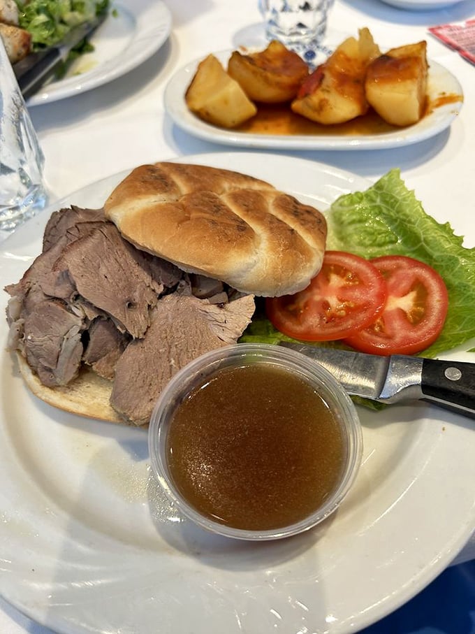 Tender roast lamb on fresh bread with a side of jus—proof that sometimes the simplest sandwiches deliver the most profound satisfaction.