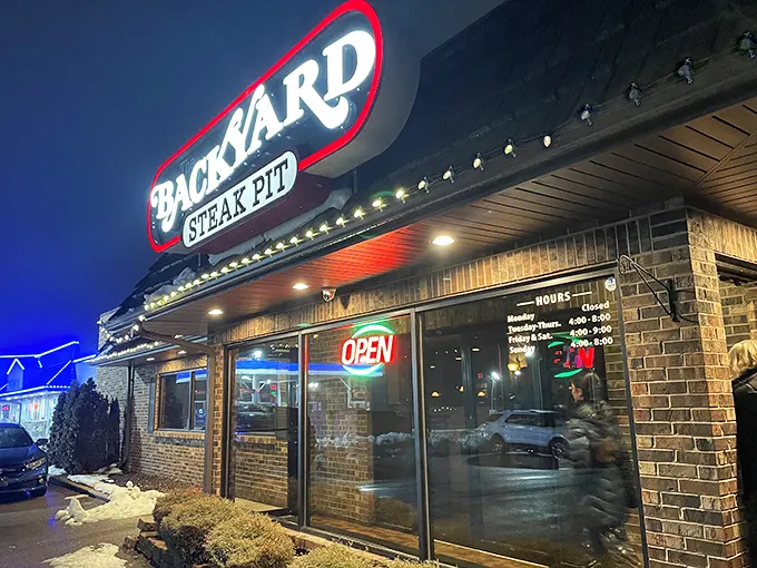 The Backyard Steak Pit's illuminated sign glows like a promise—yes, flame-grilled perfection really is waiting just inside.