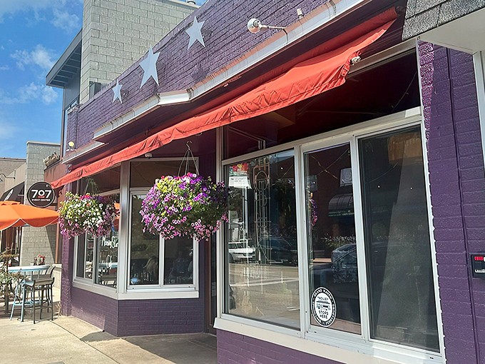 The purple facade with its cheerful red awning and hanging flower baskets isn't just eye-catching—it's nature's way of saying "breakfast is served!"