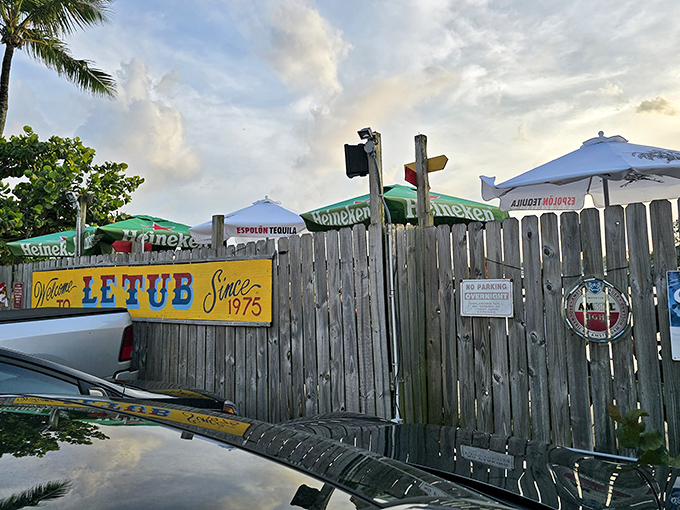The unassuming wooden fence and yellow sign of Le Tub are Florida's version of a speakeasy entrance—secrets and seafood await behind these weathered boards.