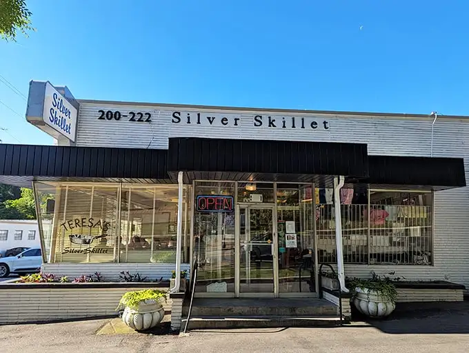 The Silver Skillet stands proudly against Atlanta's blue sky, its vintage sign a beacon for hungry souls seeking breakfast salvation in the city's bustling landscape.
