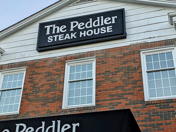 The brick façade of The Peddler stands like a carnivore's lighthouse, beckoning hungry travelers with its classic steakhouse promise. Some buildings just look delicious.