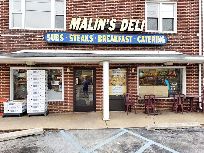 The brick-and-mortar promise of sandwich heaven – Malin's Deli stands proudly with its no-nonsense signage announcing the treasures within: SUBS • STEAKS • BREAKFAST • CATERING.