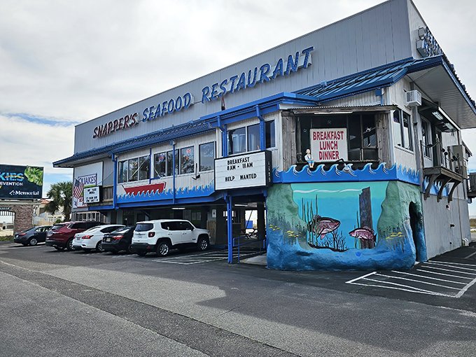 Snapper's iconic blue-trimmed exterior stands like a beacon for seafood lovers, with parking cleverly tucked underneath—Gulf Coast practicality at its finest.