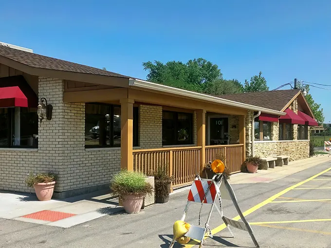 The stone sign stands like a culinary lighthouse, guiding hungry travelers to Country Charm's doorstep since 1984. Those burgundy awnings promise comfort before you even step inside.