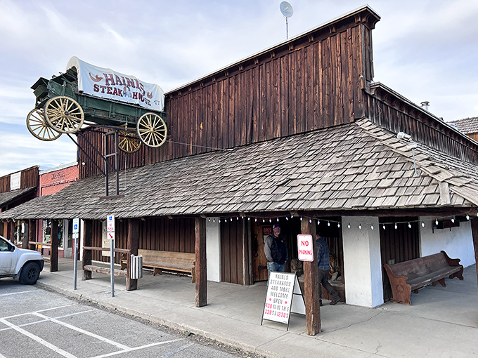 Where Western dreams meet culinary reality: The iconic covered wagon sign announces your arrival at Haines Steak House, a wooden time capsule of flavor in Eastern Oregon.