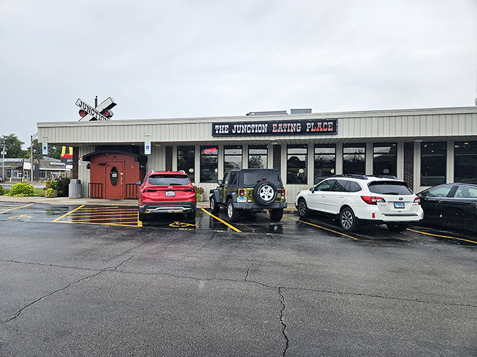 The railroad crossing sign perched atop this unassuming DeKalb diner isn't just decoration—it's a promise of the journey your taste buds are about to take.