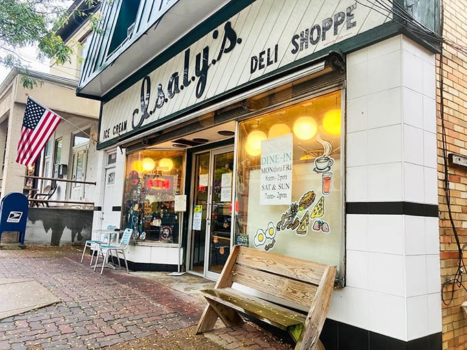 The classic storefront beckons like an old friend, complete with American flag and wooden bench – nostalgia served daily alongside the chipped ham.