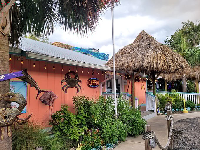 The coral-colored exterior of Kathi's Krab Shack beckons like a tropical mirage, complete with thatched roof and a giant crab announcing seafood paradise awaits.