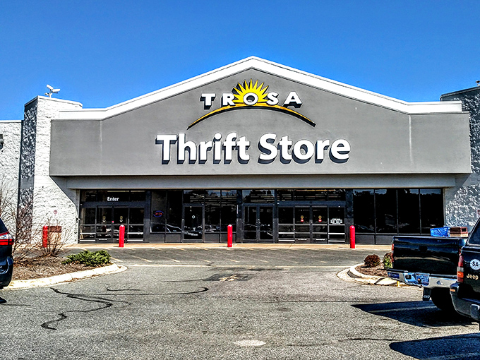 The TROSA Thrift Store stands proudly against a blue sky, its cheerful sun logo promising treasures within that are as bright as the day outside.