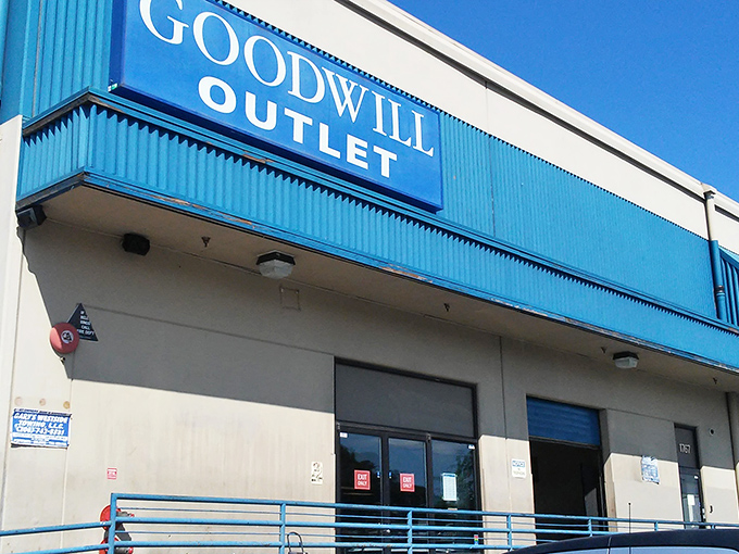 The blue-trimmed exterior of Seattle Outlet Goodwill stands like a portal to bargain dimension—where treasures await those brave enough to enter. 