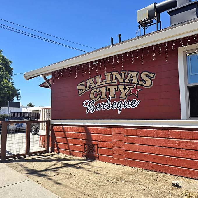 The little red house with the bright yellow door isn't trying to impress anyone—until you taste what's coming out of those smokers.