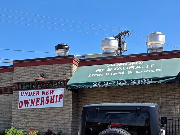 The classic roadside charm of Aurora Diner beckons hungry travelers with its promise of comfort food and that unmistakable blue-umbrella welcome.