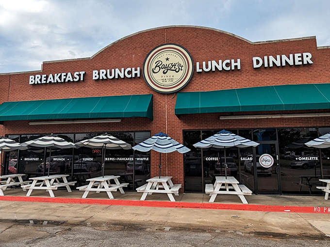 The brick facade with teal awnings isn't just inviting—it's practically shouting "Come get breakfast!" Those white picnic tables are waiting for your morning revelation.