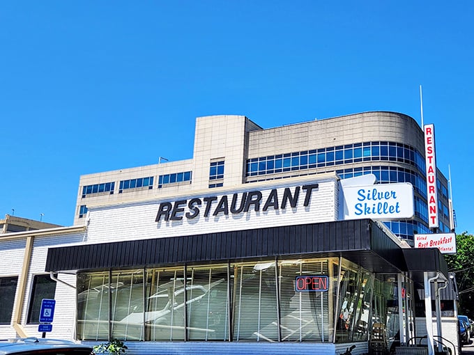The Silver Skillet stands proudly against Atlanta's blue sky, its vintage sign a beacon for hungry souls seeking breakfast salvation in the city's bustling landscape.