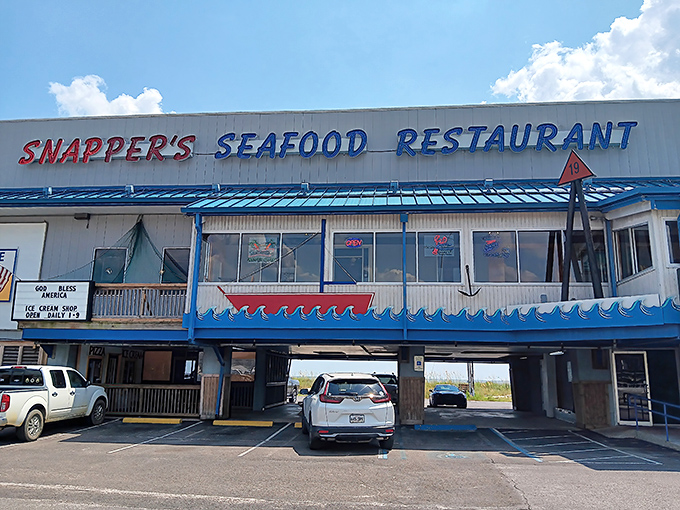 Snapper's iconic blue-trimmed exterior stands like a beacon for seafood lovers, with parking cleverly tucked underneath—Gulf Coast practicality at its finest.