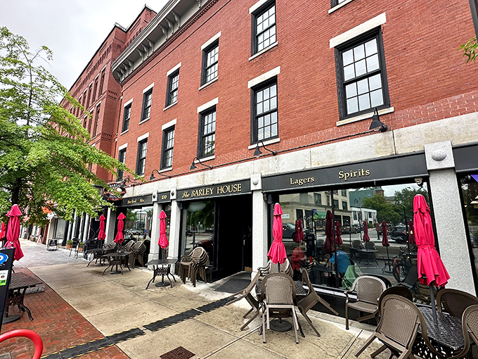 The classic red brick façade of The Barley House beckons like an old friend, with cheerful red umbrellas promising good times on the patio.