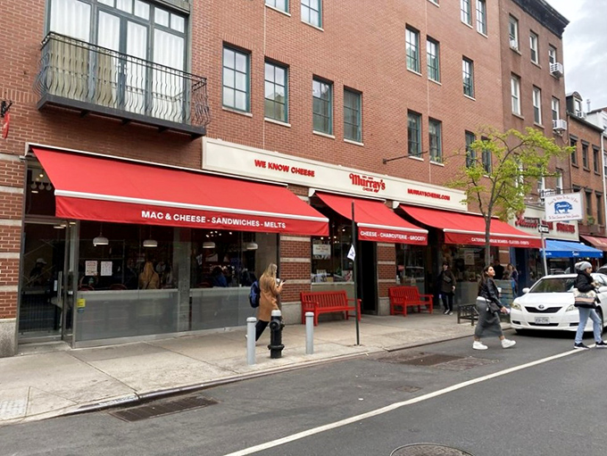 Murray's iconic storefront on Bleecker Street stands as a beacon of dairy devotion, with its signature red bench inviting cheese pilgrims to rest their weary feet before the next round.