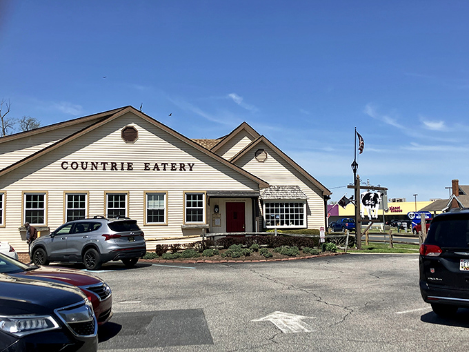 The Countrie Eatery's charming white clapboard exterior with its iconic cow sign promises comfort food paradise before you even step through the door.