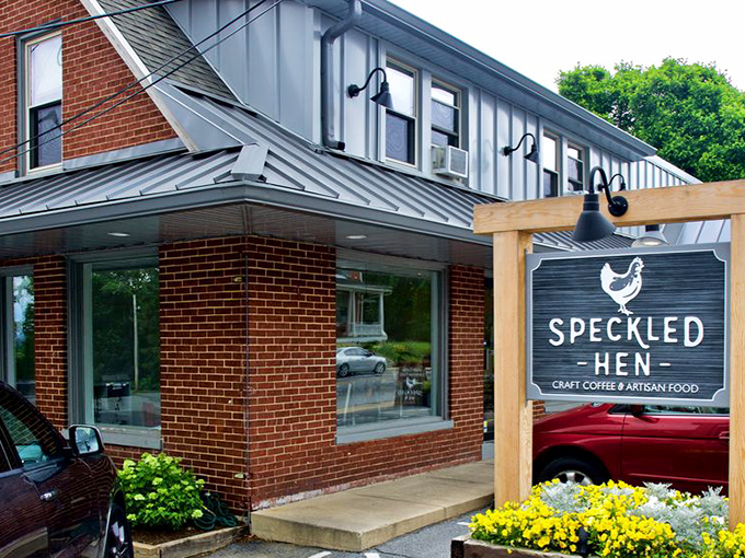 The charming brick exterior of Speckled Hen welcomes hungry travelers with its rustic wooden sign and seasonal decorations—breakfast paradise found in Strasburg!