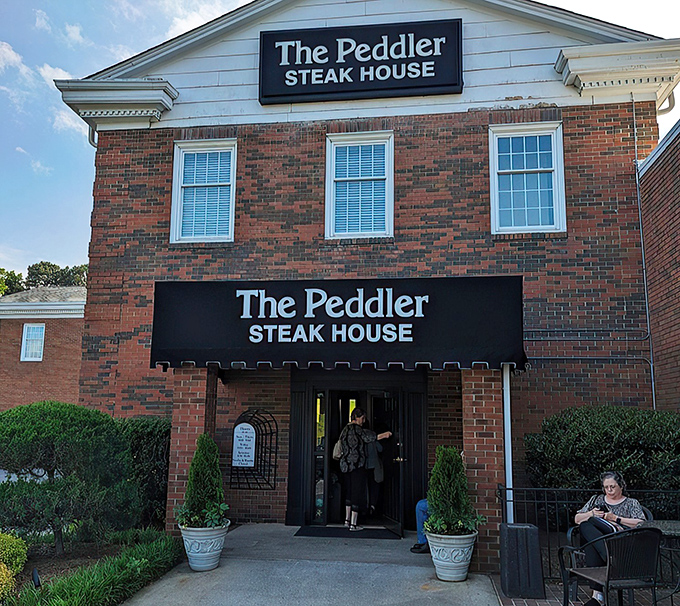 The brick façade of The Peddler stands like a carnivore's lighthouse, beckoning hungry travelers with its classic steakhouse promise. Some buildings just look delicious.