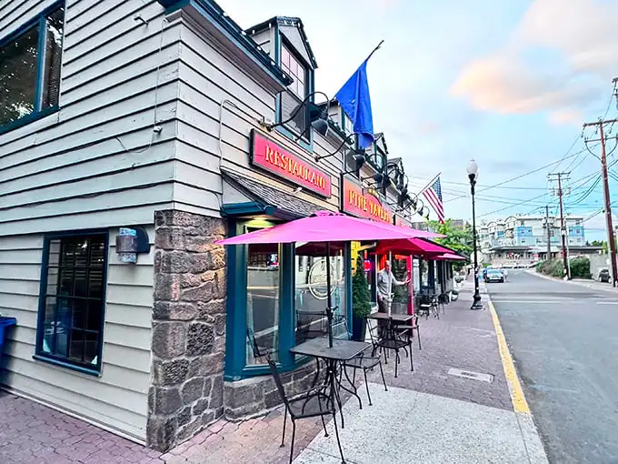 The charming exterior of Pine Tavern beckons with its classic red awning and stone facade, a timeless landmark in downtown Bend since the Great Depression era.