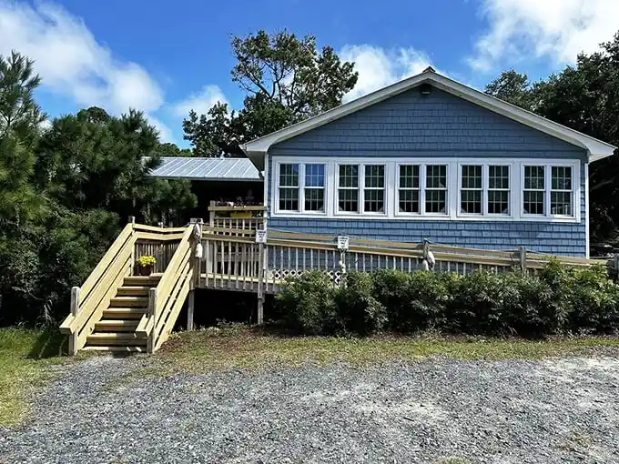 A coastal cottage that promises culinary magic. The wooden staircase leads to seafood heaven disguised as an unassuming green-shingled home.