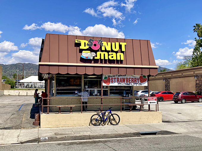The iconic brown A-frame building stands proudly along Route 66, beckoning donut pilgrims with its cheerful signage and promise of strawberry-filled bliss.