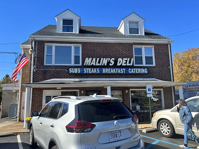 The brick-and-mortar promise of sandwich heaven – Malin's Deli stands proudly with its no-nonsense signage announcing the treasures within: SUBS • STEAKS • BREAKFAST • CATERING.