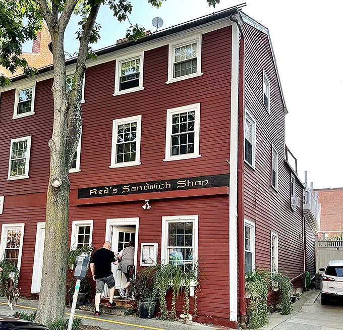 The iconic crimson colonial exterior of Red's Sandwich Shop stands as proudly in Salem as Paul Revere once did, beckoning hungry visitors with historical charm.